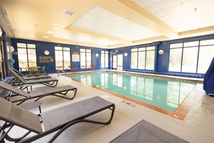 Piscina interna com regras de utilização afixadas na parede, cadeira de salva-vidas e escada para piscina.