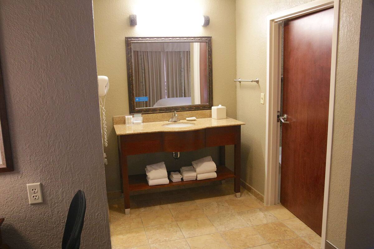 Casa de banho com lavatório, espelho, porta-toalhas e porta.