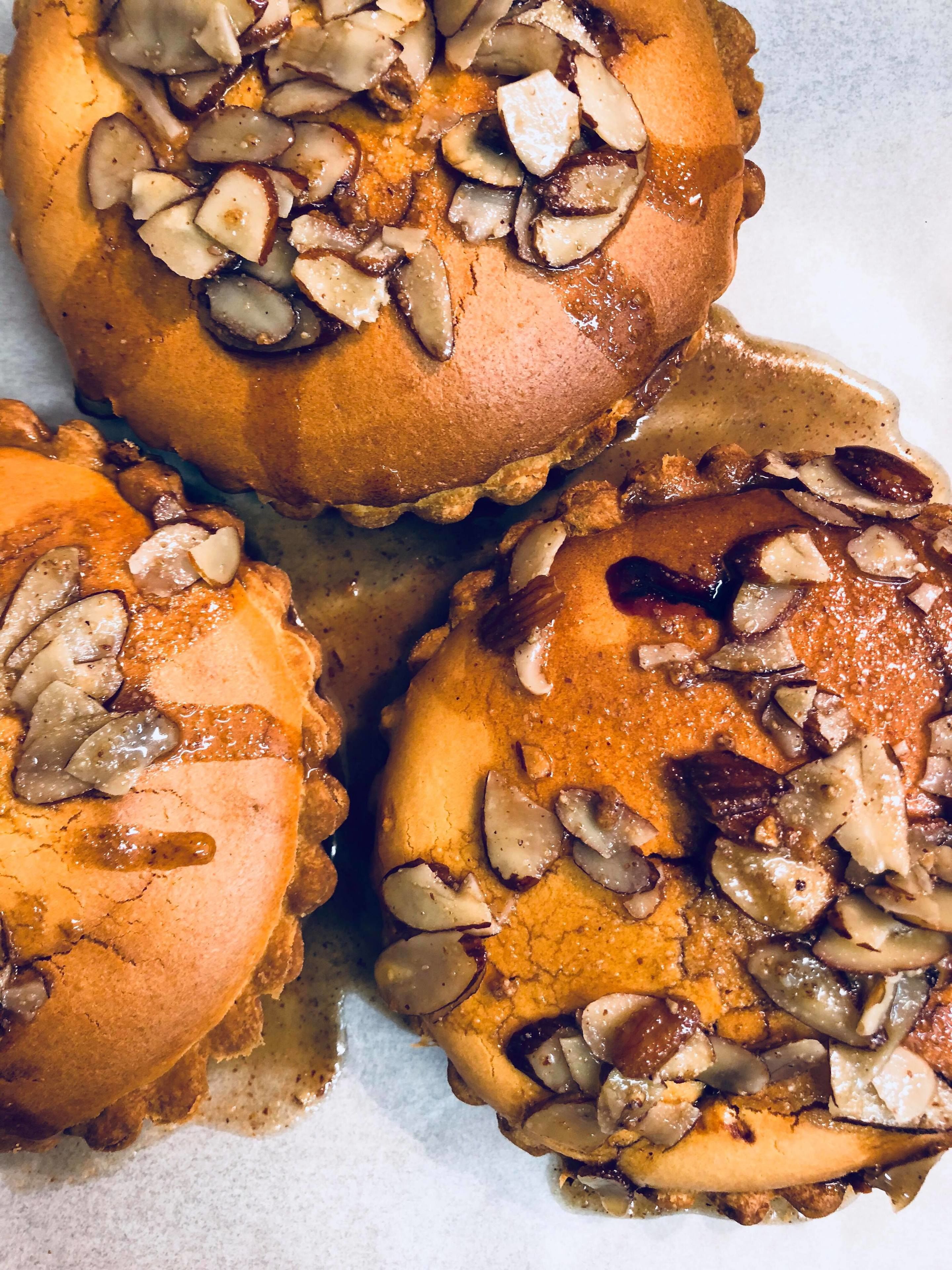 Três cinnamon rolls cobertos com amêndoas fatiadas.