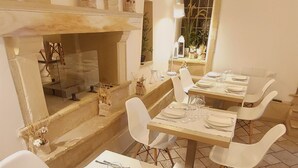 Restaurante com toalhas de mesa brancas, lareira de pedra e vista para o exterior.