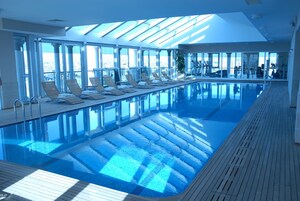 Uma grande piscina interna com áreas banhadas pelo sol e espreguiçadeiras.