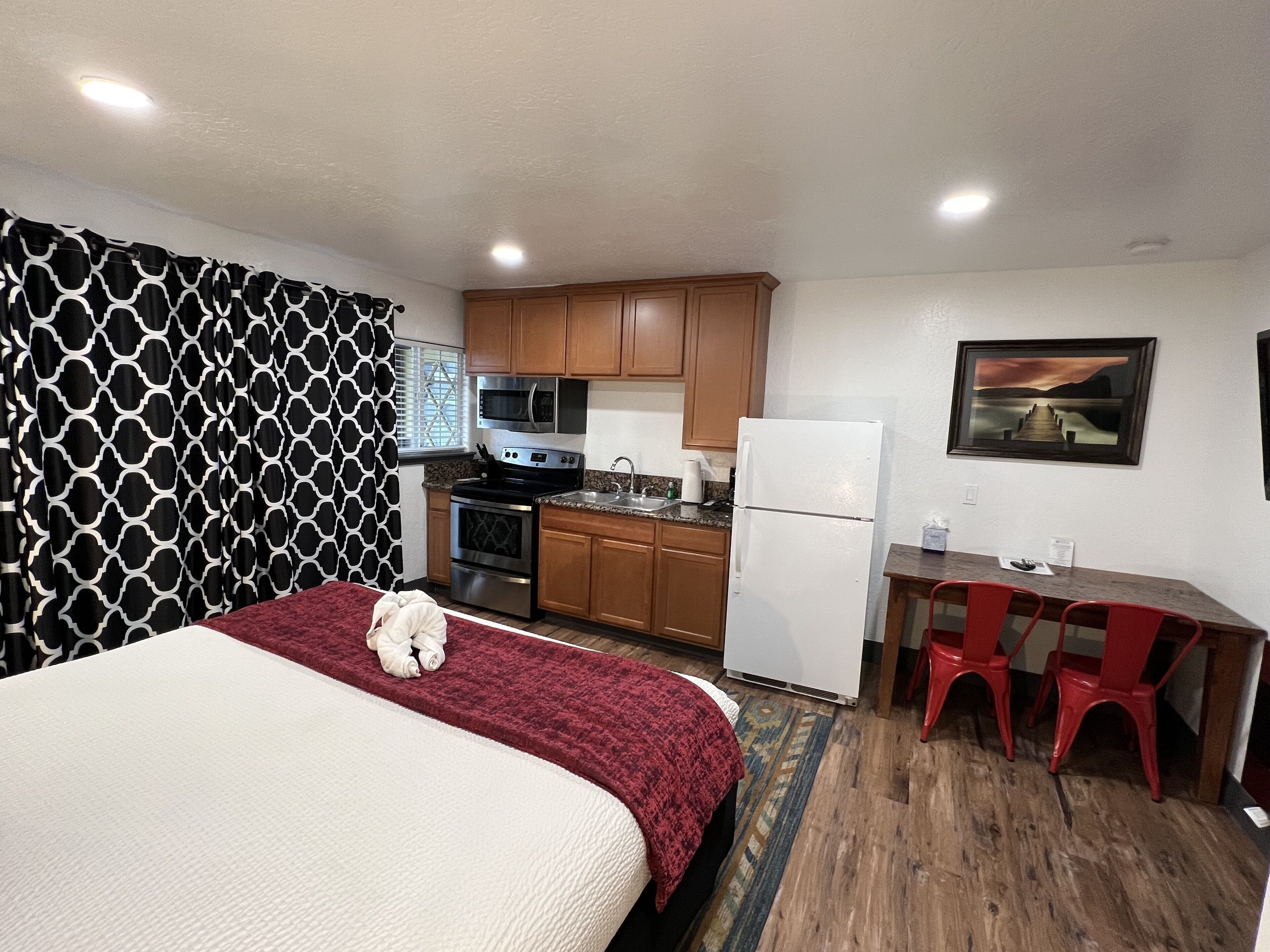 Quarto compacto com cama, cozinha compacta e pequena área de refeições.