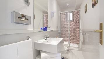 Uma casa de banho moderna com uma sanita, um lavatório branco e uma cabine de duche em vidro.