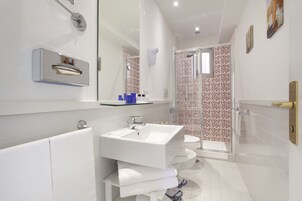 Uma casa de banho moderna com uma sanita, um lavatório branco e uma cabine de duche em vidro.