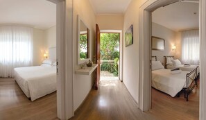 Quarto de hotel com duas camas, varanda e vista para o verde.