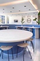 Um hall de hotel moderno com uma grande mesa redonda, área de bar e assentos.