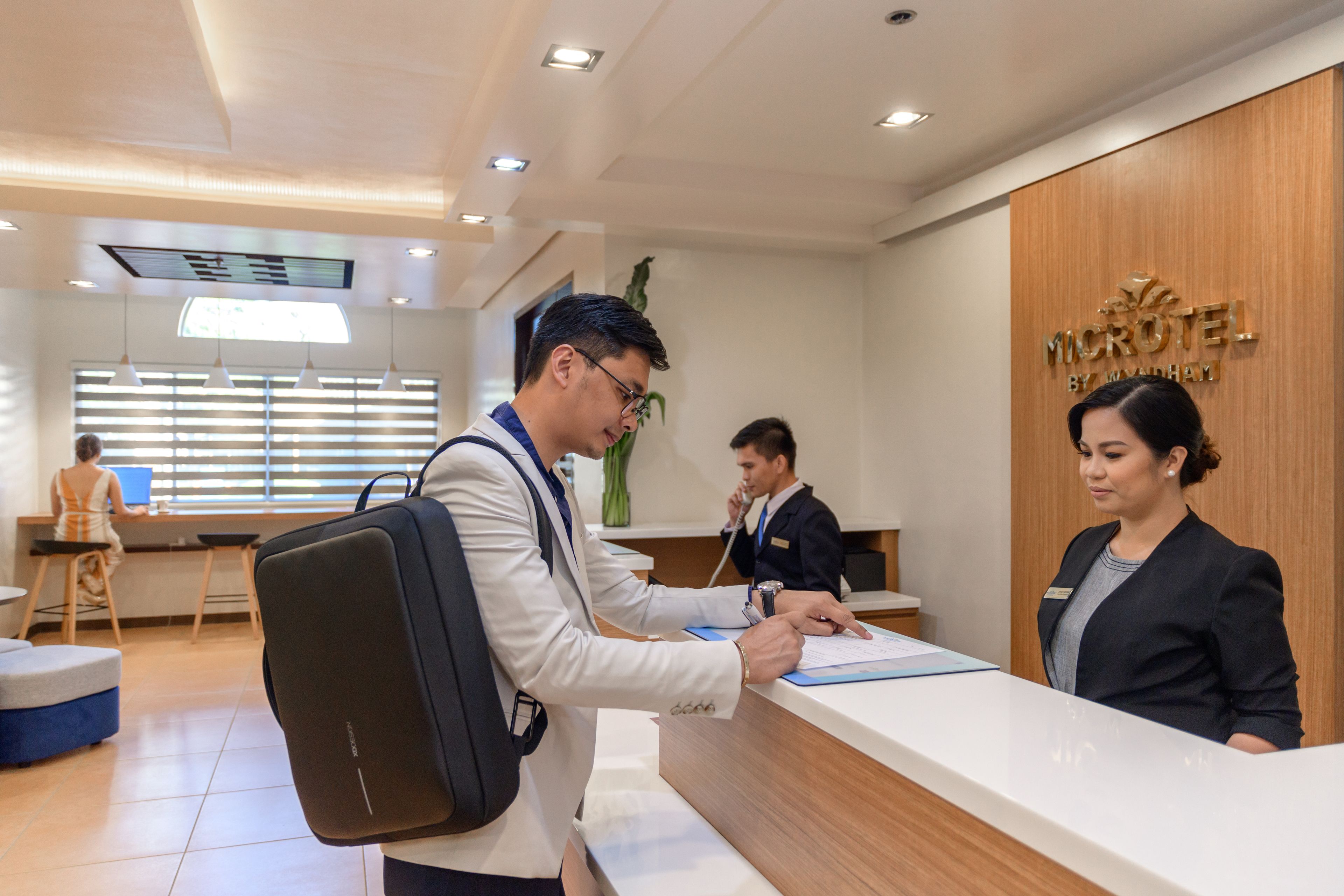 Balcão de recepção de hotel com recepcionista e hóspede.