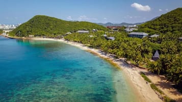 Um resort costeiro com águas turquesa cristalinas, uma praia arenosa e colinas verdes exuberantes.