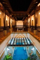 Uma área de piscina com barreira de vidro, guarda-corpos de madeira e assentos.