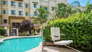 Piscina com espreguiçadeira e rampa acessível para cadeiras de rodas.