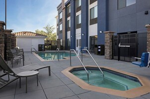 Um hotel com piscina, espreguiçadeiras e um terraço coberto.
