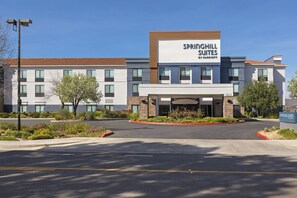 Um hotel com design moderno, exibindo uma placa chamativa de 'SPRINGHILL SUITES BY MARRIOTT' e um acesso direto ao saguão.