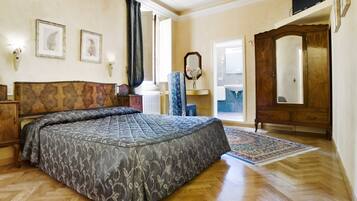 Quarto com uma cama grande, um guarda-roupa de madeira, um espelho e um radiador.