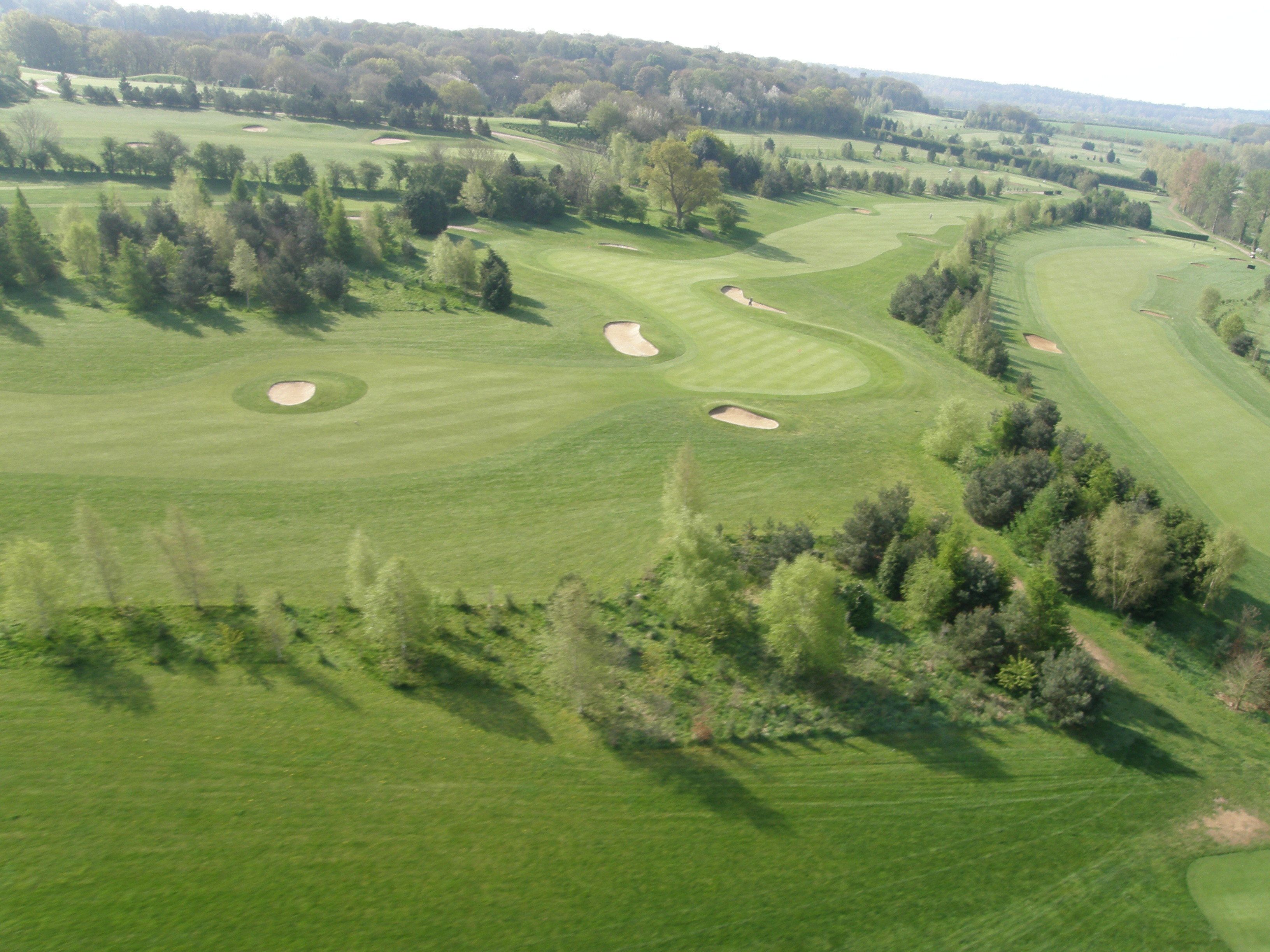 Vista aérea de um campo de golfe com vários bunkers e árvores.
