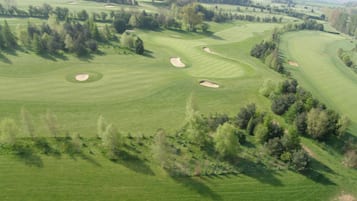 Vista aérea de um campo de golfe com vários bunkers e árvores.