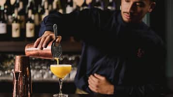 Um bartender a servir uma bebida num copo de martini.
