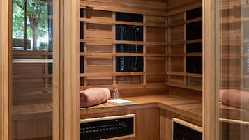 Uma sauna com paredes e bancos de madeira, uma porta de vidro e uma toalha em um dos bancos.