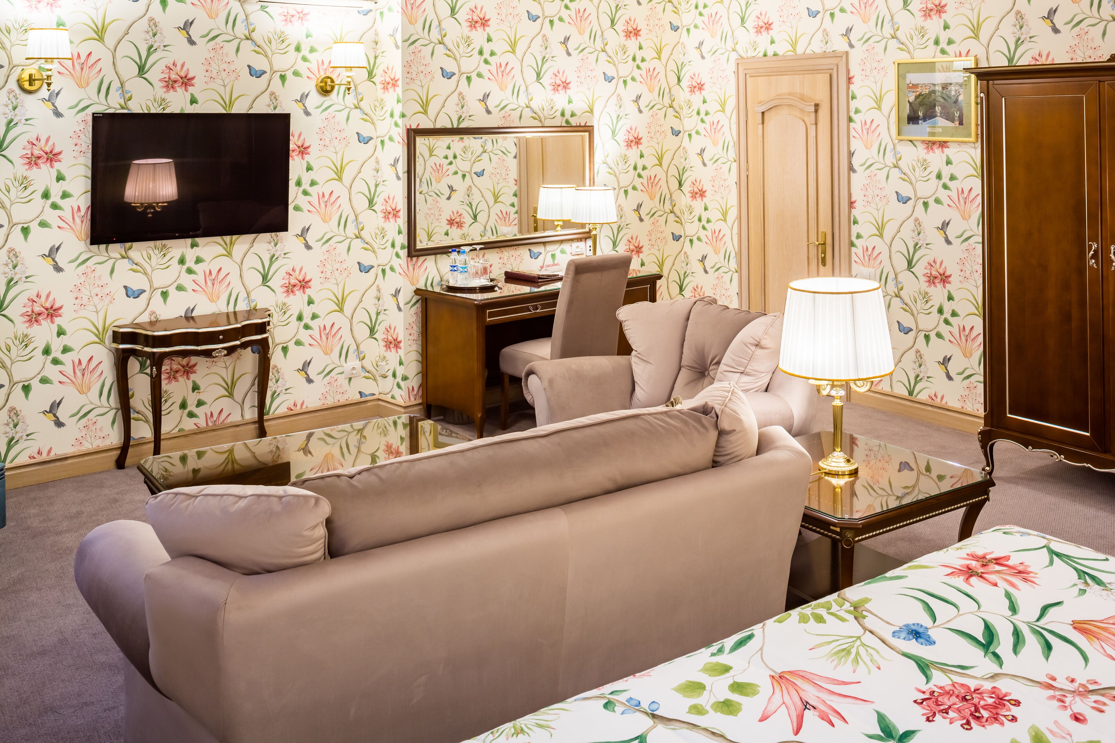 Quarto de hotel com sofá, escrivaninha, televis ão e guarda-roupa.