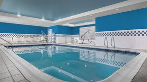 Piscina interior com borda de azulejos quadriculada, esquema de cores azul e branco e chão revestido com azulejos.