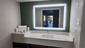 Casa de banho com toucador branco, espelho grande e parede verde.