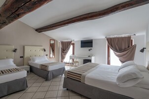 Quarto de hotel com duas camas, uma escrivaninha, uma cadeira e uma televisão.