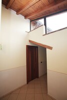 Um corredor estreito com teto de madeira e uma porta no final.
