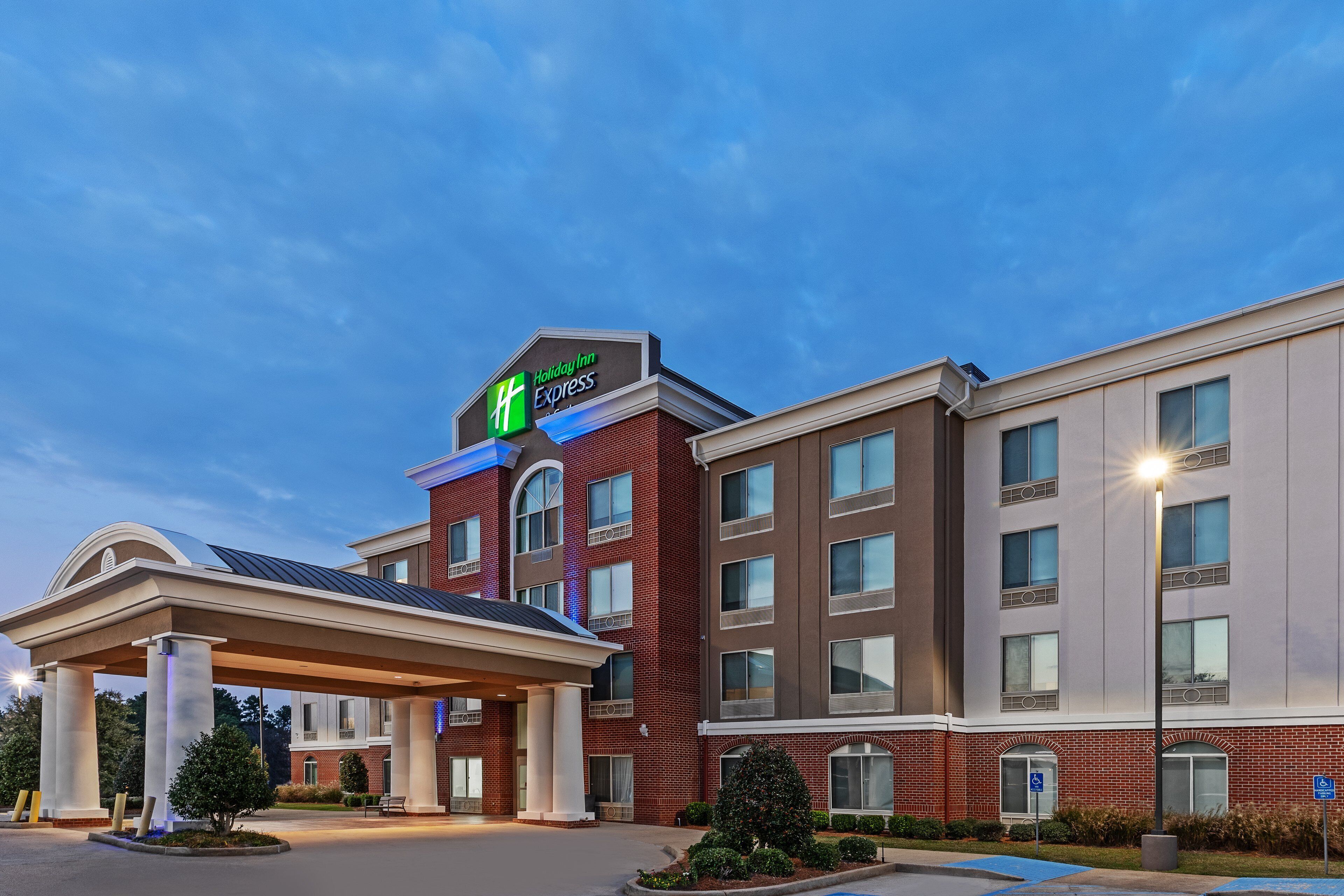Um hotel Holiday Inn Express com área externa coberta, vários andares e céu claro.