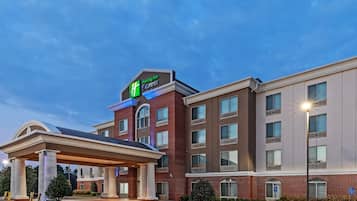 Um hotel Holiday Inn Express com área externa coberta, vários andares e céu claro.
