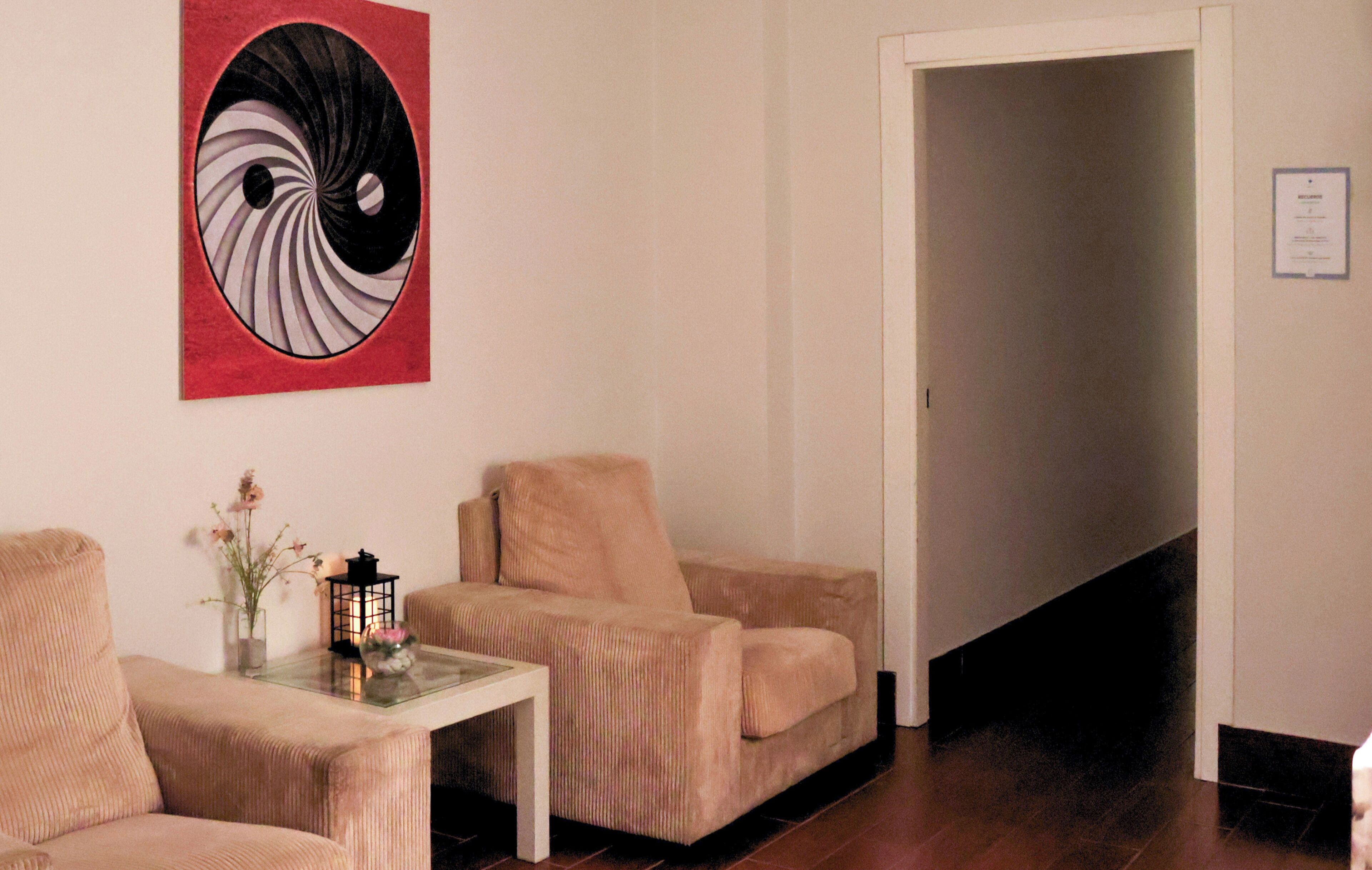 Quarto com sofá bege, mesa de centro de vidro e pintura abstrata moderna na parede.