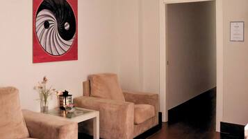 Quarto com sofá bege, mesa de centro de vidro e pintura abstrata moderna na parede.