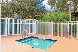 Pequena piscina coberta com cerca branca, aviso de proibição de saltos e placa com regras da piscina.