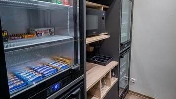 Uma cozinha moderna com micro-ondas embutido, frigorífico com porta de vidro e estantes de madeira.