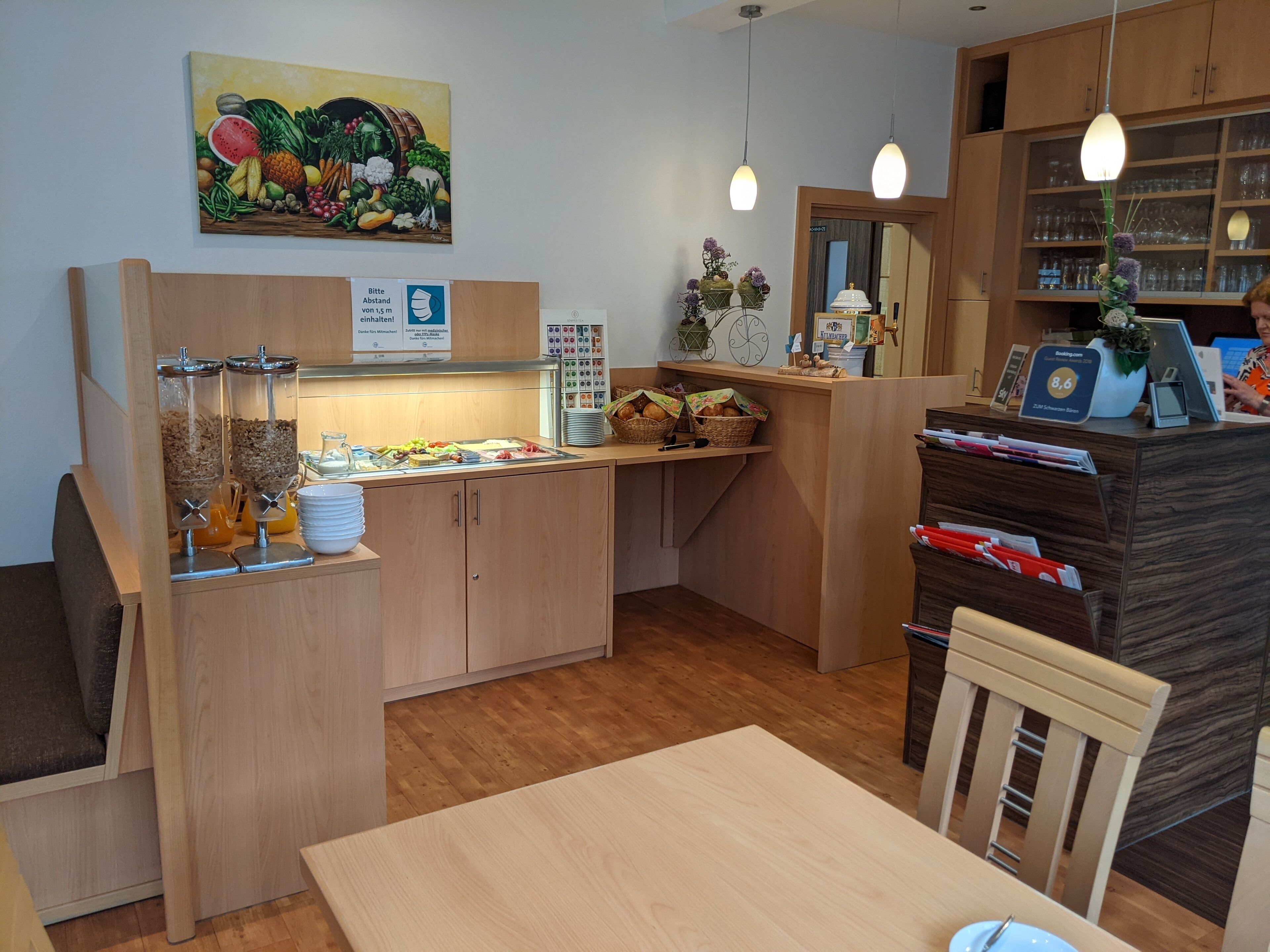 Um balcão de café da manhã com diversos alimentos e uma pintura de frutas e legumes na parede.