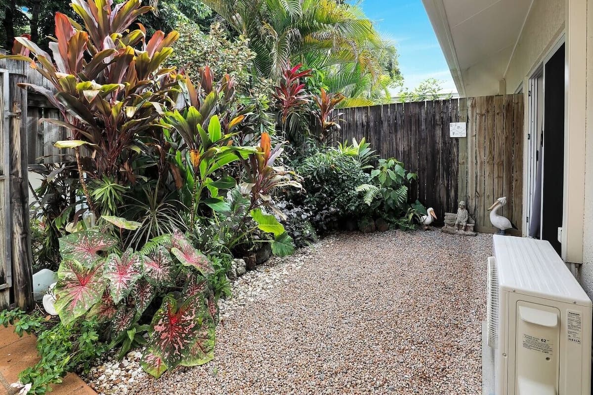 Um jardim com diversas plantas e um caminho de cascalho.