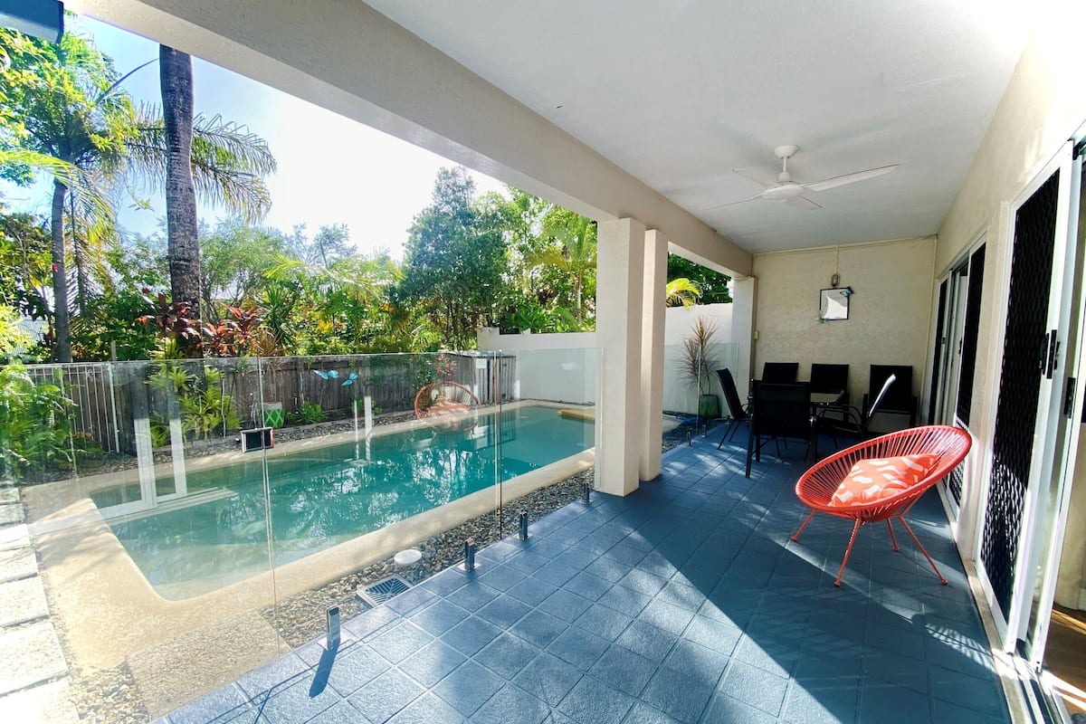 Espaço ao ar livre coberto com piscina, assentos e vista para o verde.