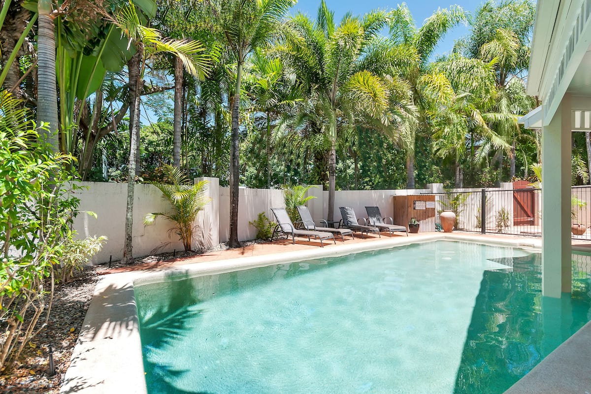Piscina com espreguiçadeiras e palmeiras.