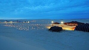 Uma praia nevada com tendas e uma fileira de luzes.