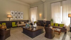 Uma sala de estar espaçosa com uma mesa de centro, sofás e cadeiras dispostos ao redor.