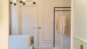 Quarto de hotel moderno com porta branca, um esguicho de metal preto para roupas e um sofá branco.
