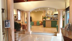 Um hall com balcão de atendimento, área de estar e bar.