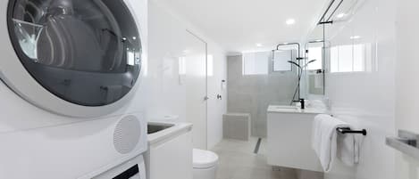 Casa de banho moderna com máquina de lavar integrada, sanita e zona de duche.