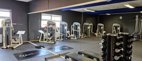 Uma academia com diversos equipamentos de exercício, colchonetes e pesos.