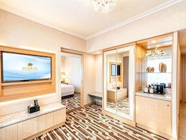 Quarto de hotel com televisão, cama, banheiro com espelho e toucador com amenities.