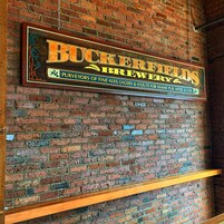 Uma parede de tijolos com uma placa para a cervejaria Buckfields.