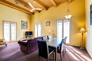 Uma sala de estar ampla com uma grande mesa de jantar, assentos confortáveis e um ventilador de teto.