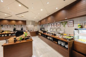 Disposição de buffet com diversos alimentos e um espaço para café.