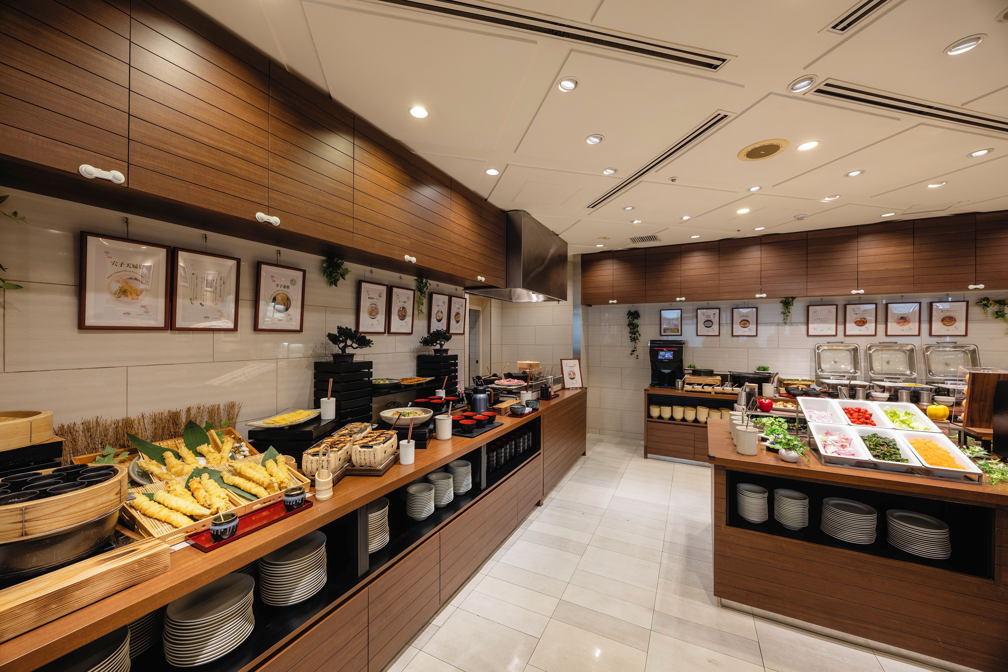 Uma área de buffet com diversos pontos de serviço e um balcão extenso repleto de alimentos.