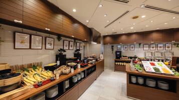 Uma área de buffet com diversos pontos de serviço e um balcão extenso repleto de alimentos.