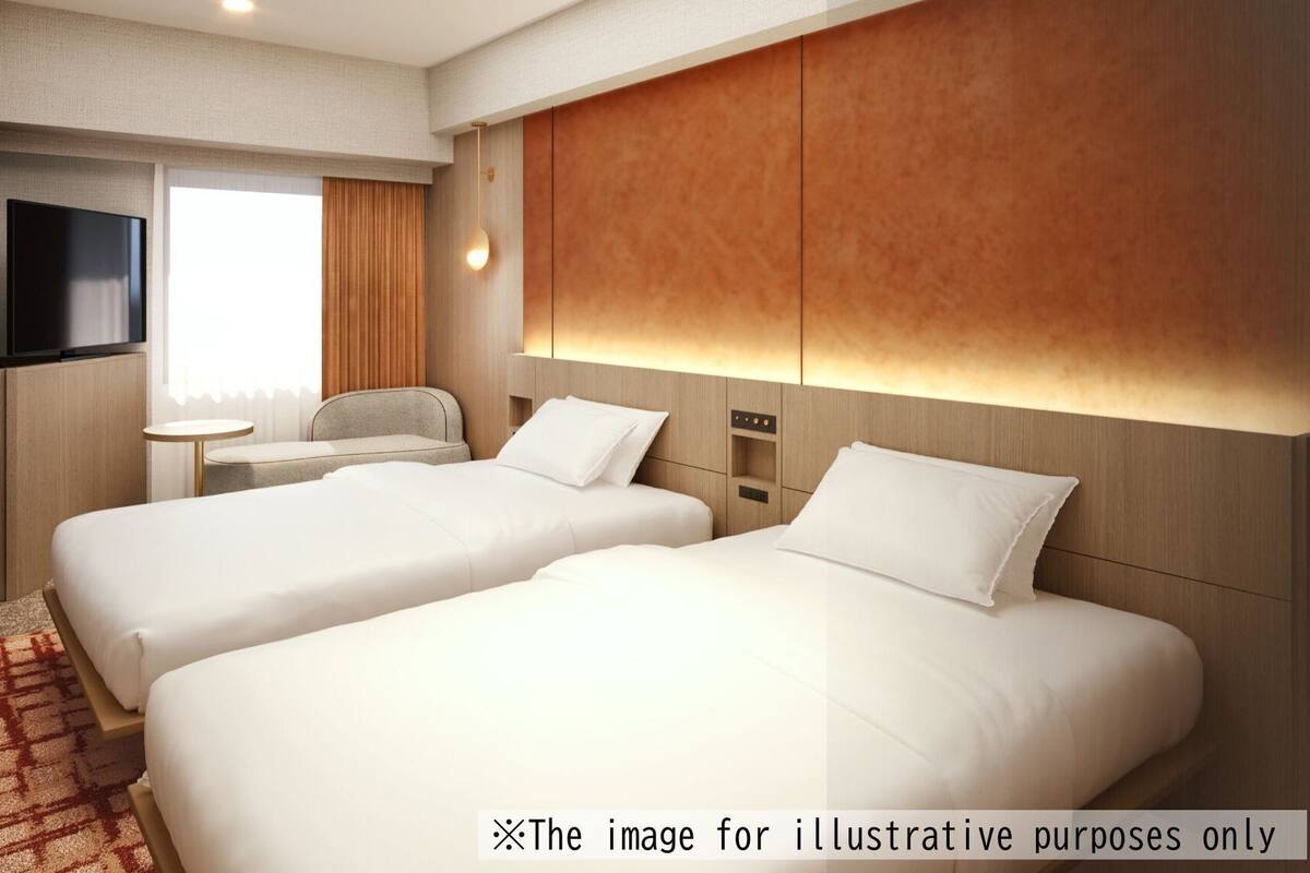 Quarto de hotel com duas camas, televisão, uma mesa pequena e janela com cortinas.