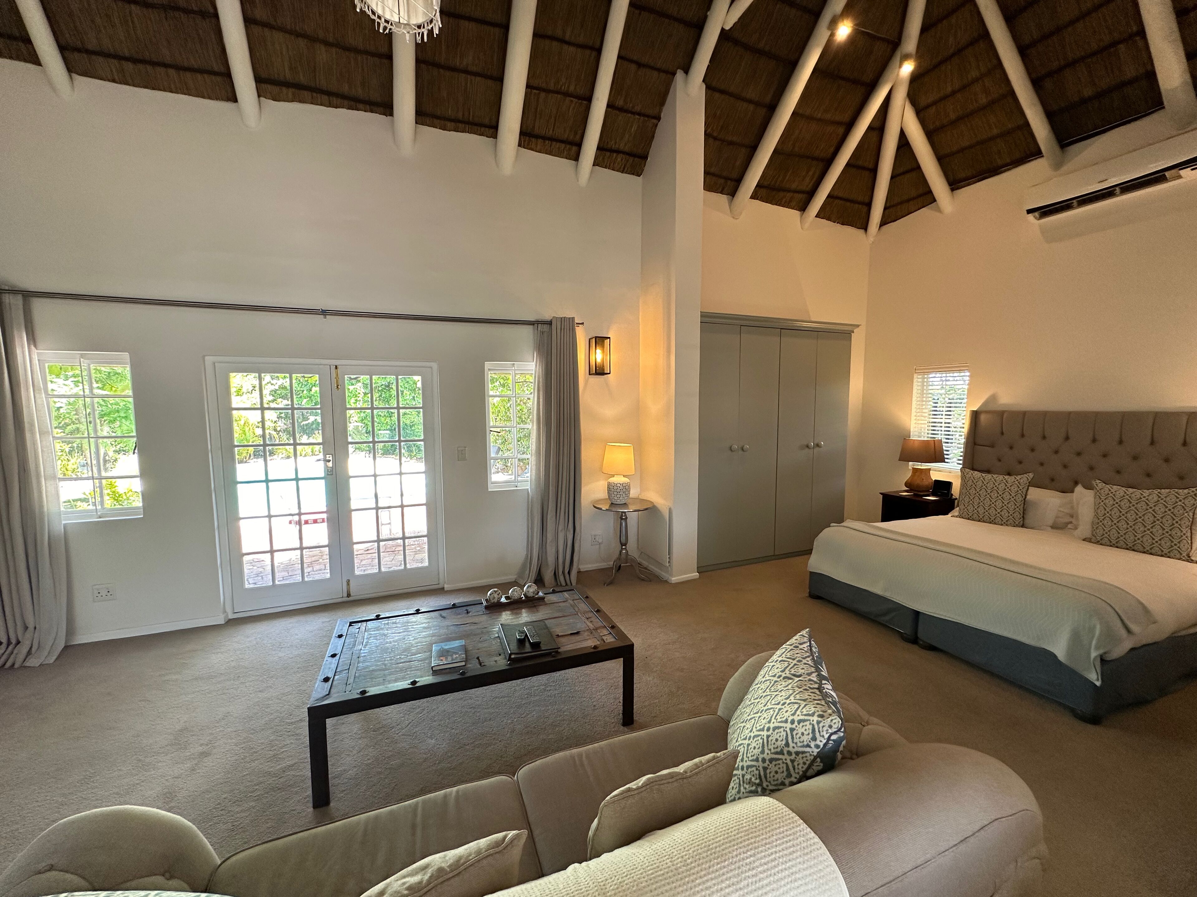 Um quarto espaçoso com uma cama grande, um sofá, uma mesa de centro e um guarda-roupa.